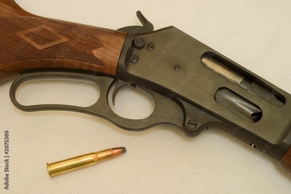 cowboy style lever-action rifle with a single cartridge by its side ...