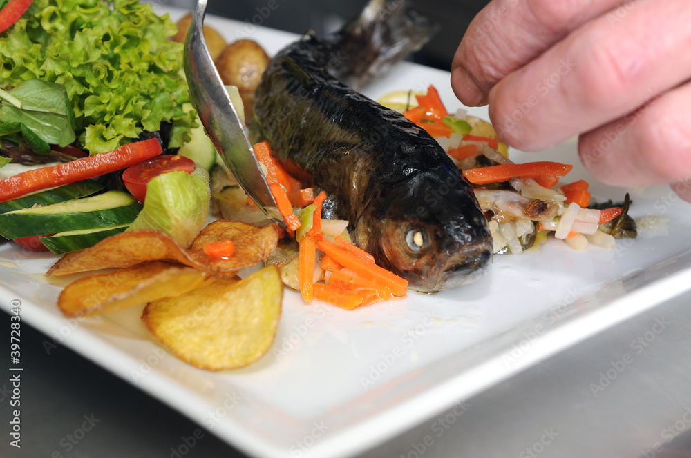 der Koch richtet das Essen an - Forelle aus dem Ofen Stock Photo ...