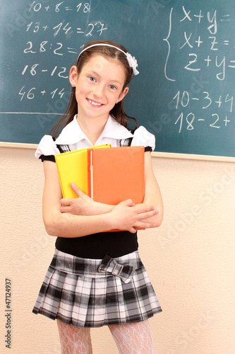 beautiful little girl in school uniform with books in class Stock Photo ...