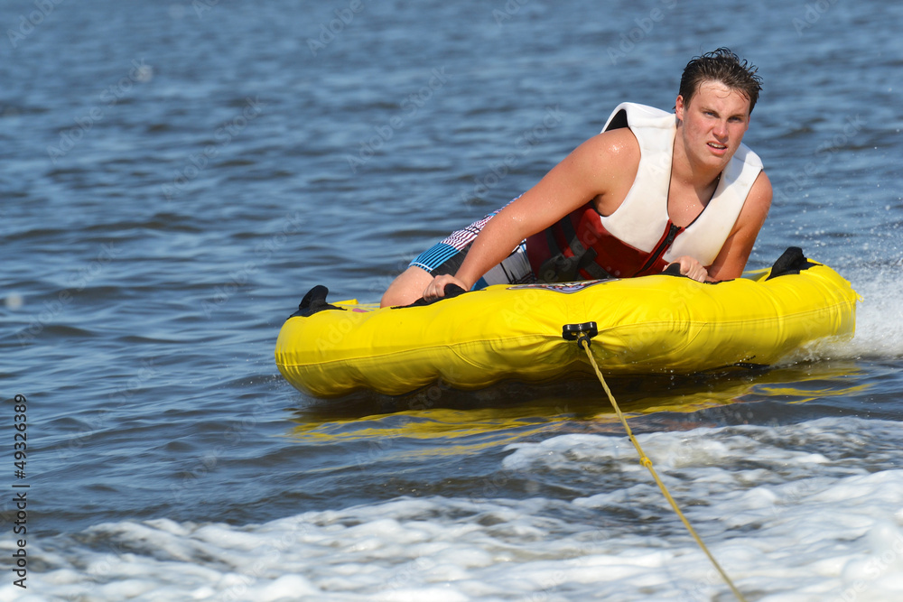 Teenage Tuber Looking Back to the Boat Wake の Stock フォト | Adobe Stock