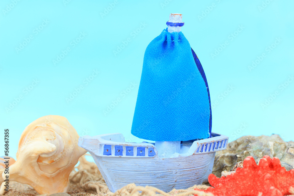 Blue toy ship on sand, on blue background Stock Photo | Adobe Stock