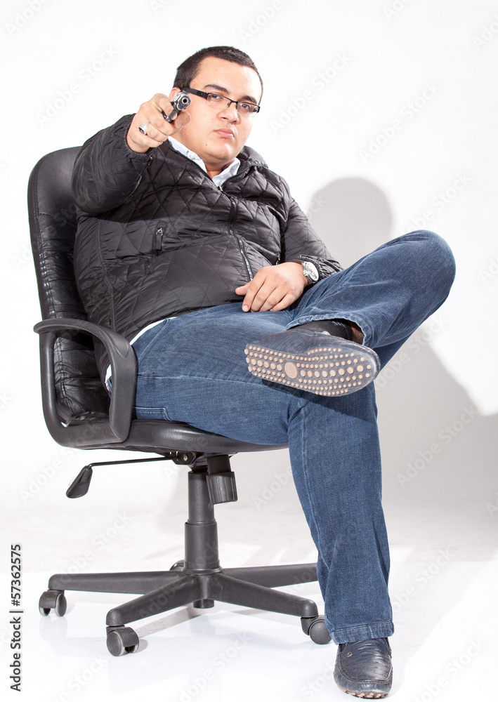 Serious man sitting on chair and aiming with gun at camera Stock Photo ...