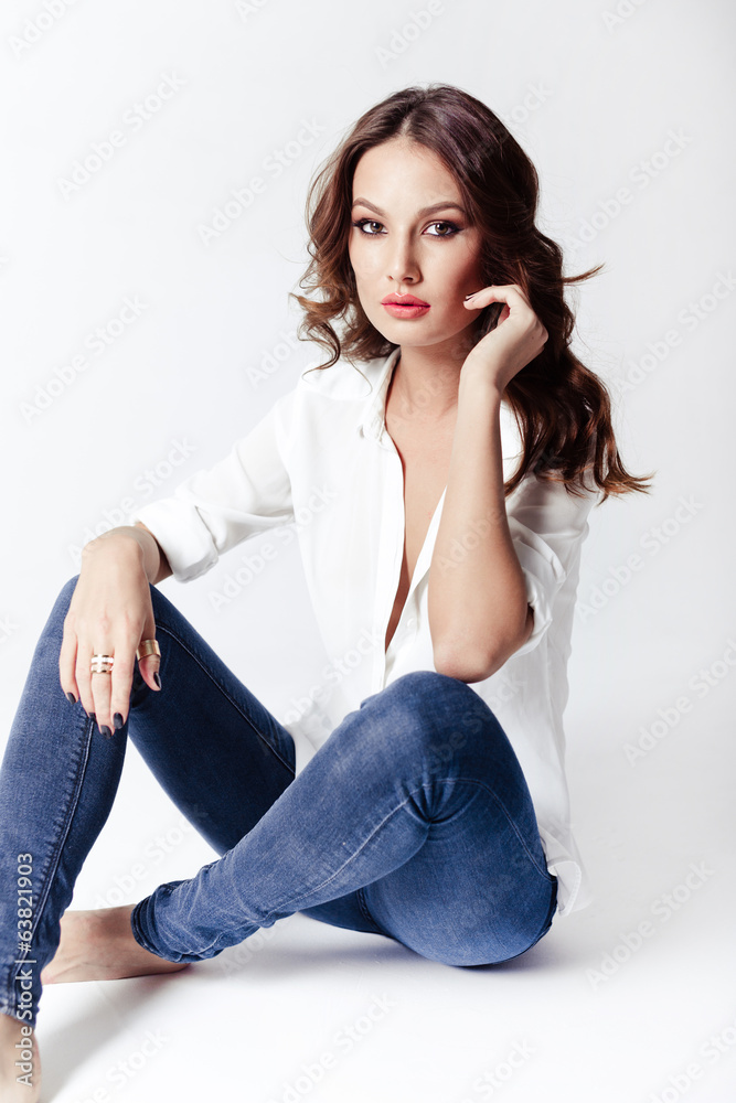 Fashion model sitting on a floor in a blouse and jeans barefoot Stock ...