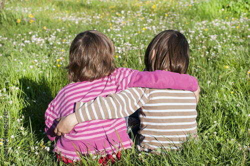 Two children sitting back together on rural meadow – kaufen Sie dieses ...