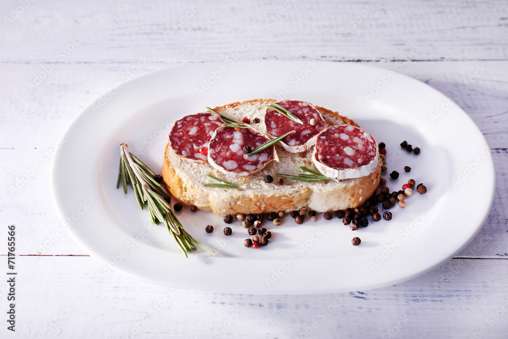 Sandwich with salami on plate on wooden background Stock Photo | Adobe ...