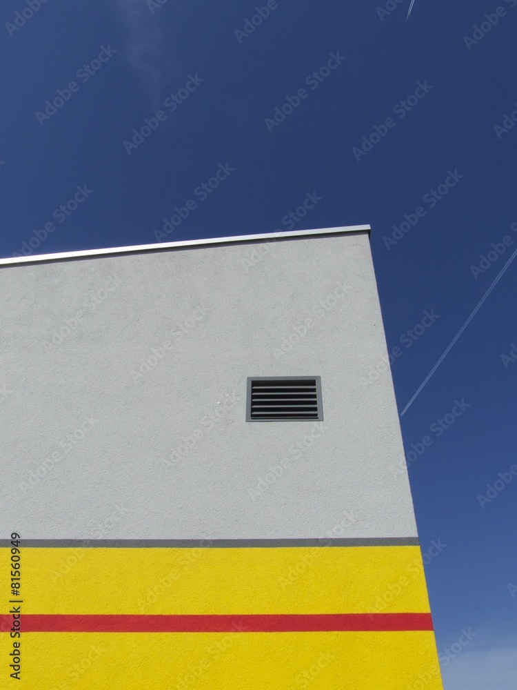 Stock-Foto „Fassade eines Gewerbebau in Gelb und Naturfarben mit rotem Streifen vor blauem ...