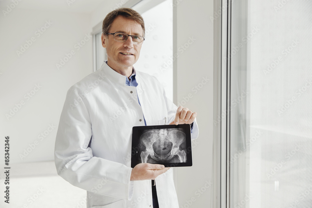 Mature man in lab coat presenting an x-ray scan on his digital tablet ...