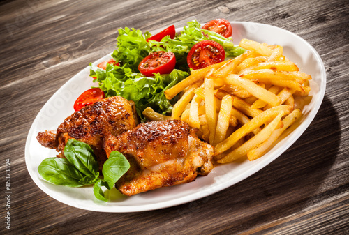 Grilled chicken legs with chips and vegetables Stock Photo | Adobe Stock