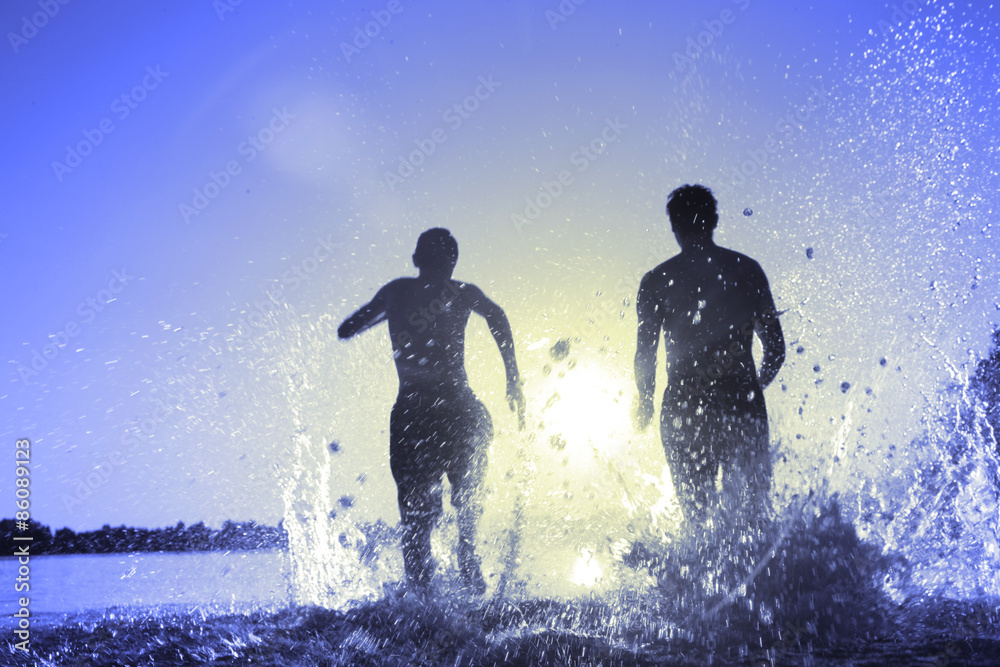 Glückliche junge Menschen laufen und springen am See beim ...