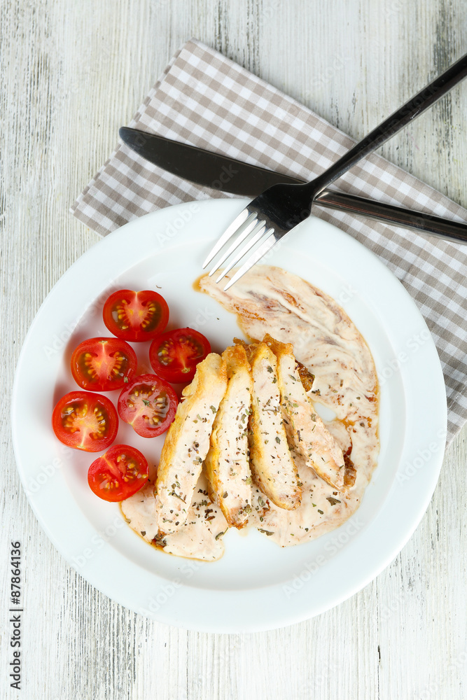 Slices of chicken fillet with spices and cherry tomato on table close ...
