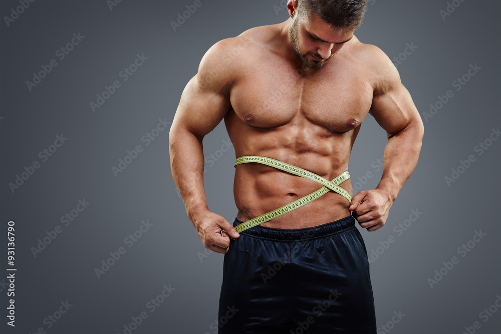 Fitness male model measuring his waist with tape measure isolated over ...
