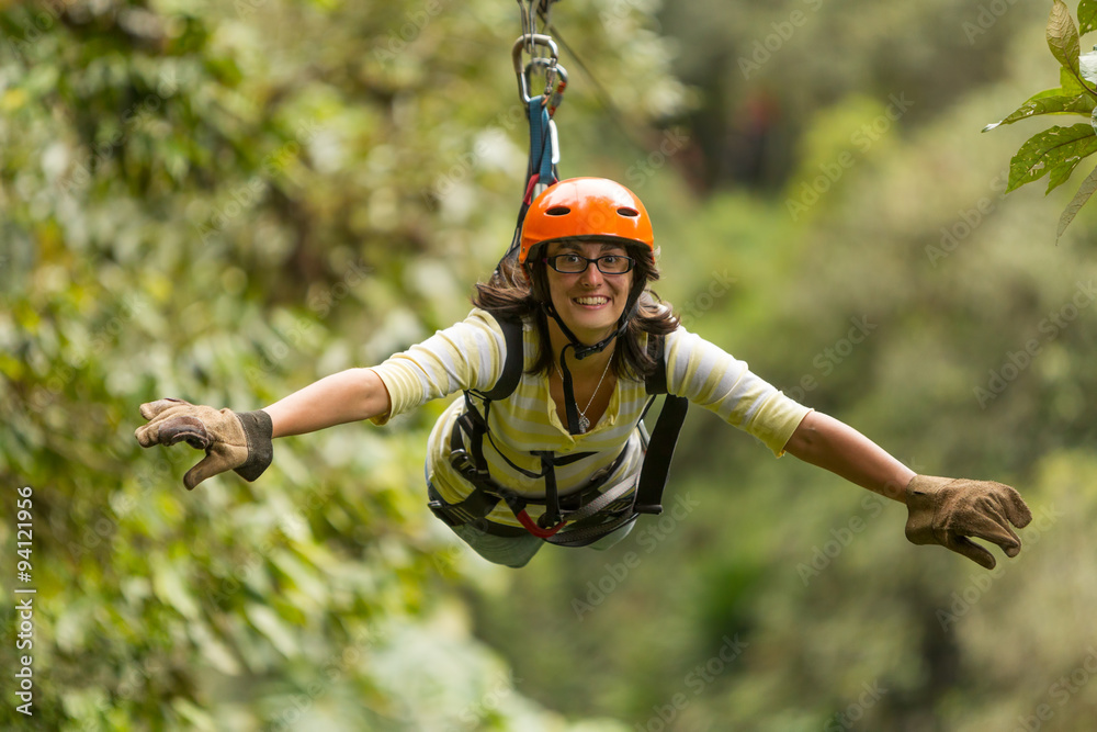 A woman ziplining through the lush rainforest of Ecuador, feeling the ...