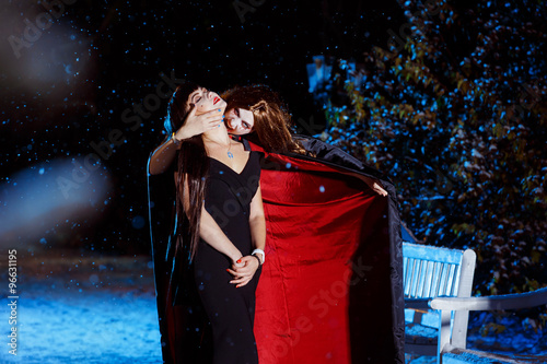 Beautiful female vampire in long pallium is biting her victim - Buy ...