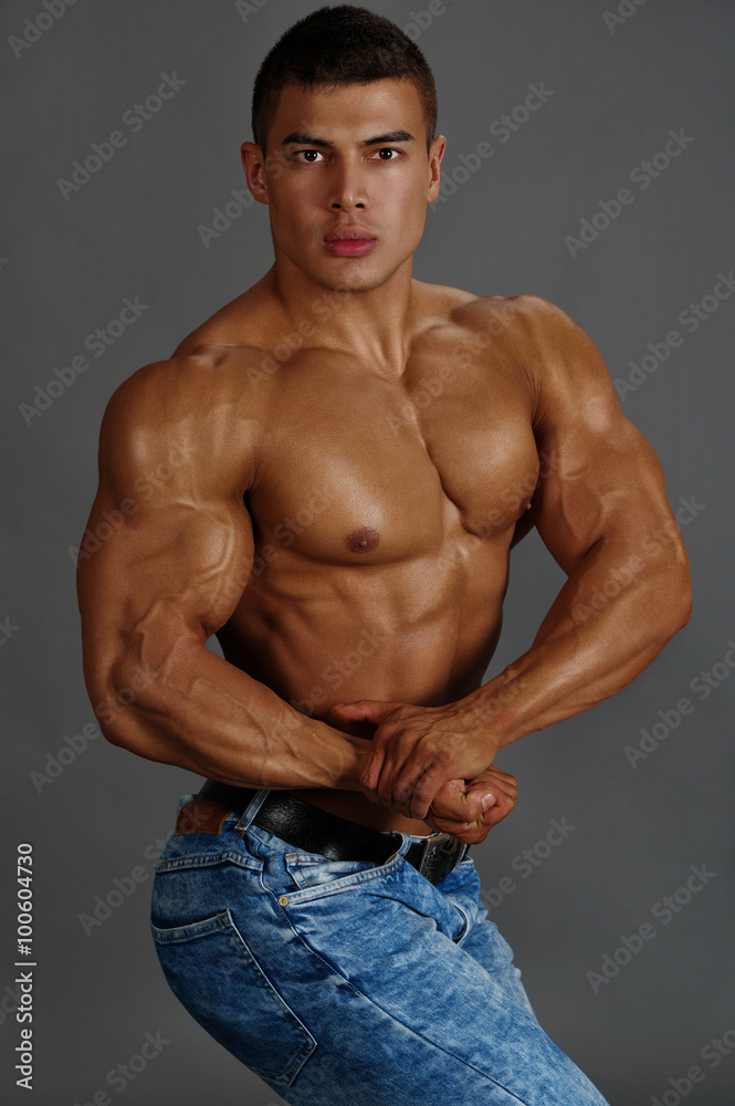 Muscular man in jeans posing, showing biceps. Stock Photo | Adobe Stock