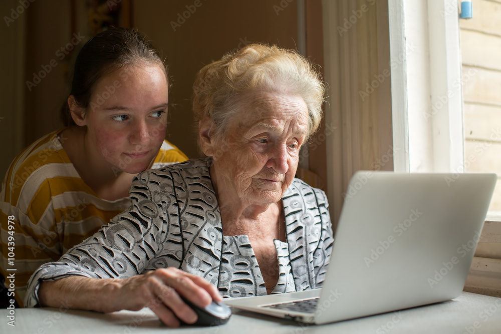 Granddaughter teaches her grandmother to type on the laptop. Stock ...