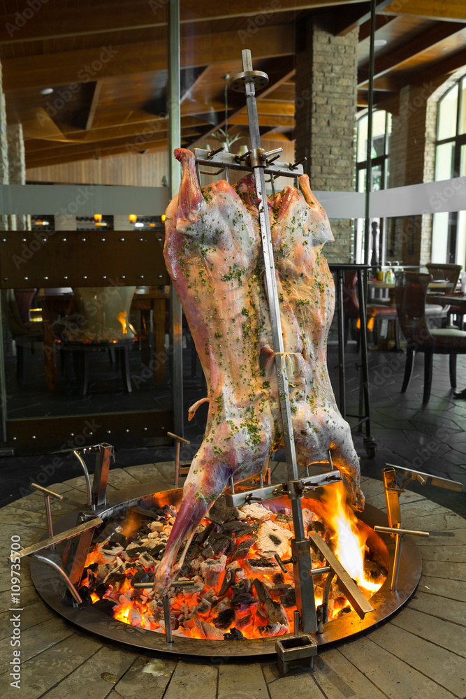 Delicious organic Whole Roasted goat on a Spit roast rack over a hot ...