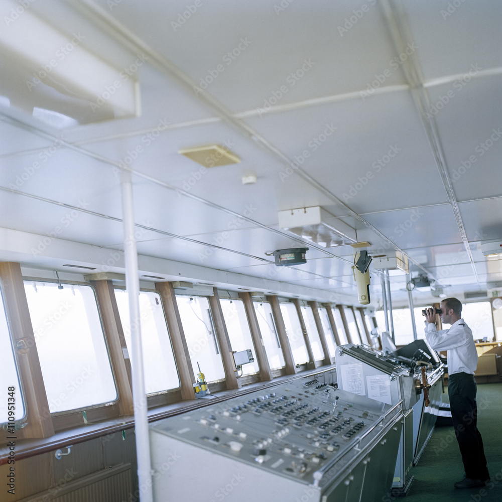 Sailor using binoculars on bridge of container ship at sea Stock Photo ...