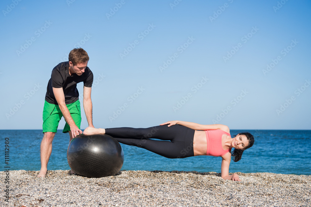 Sport und Fitness Trainer zeigt junger Frau wie man mit Gymnastikball ...