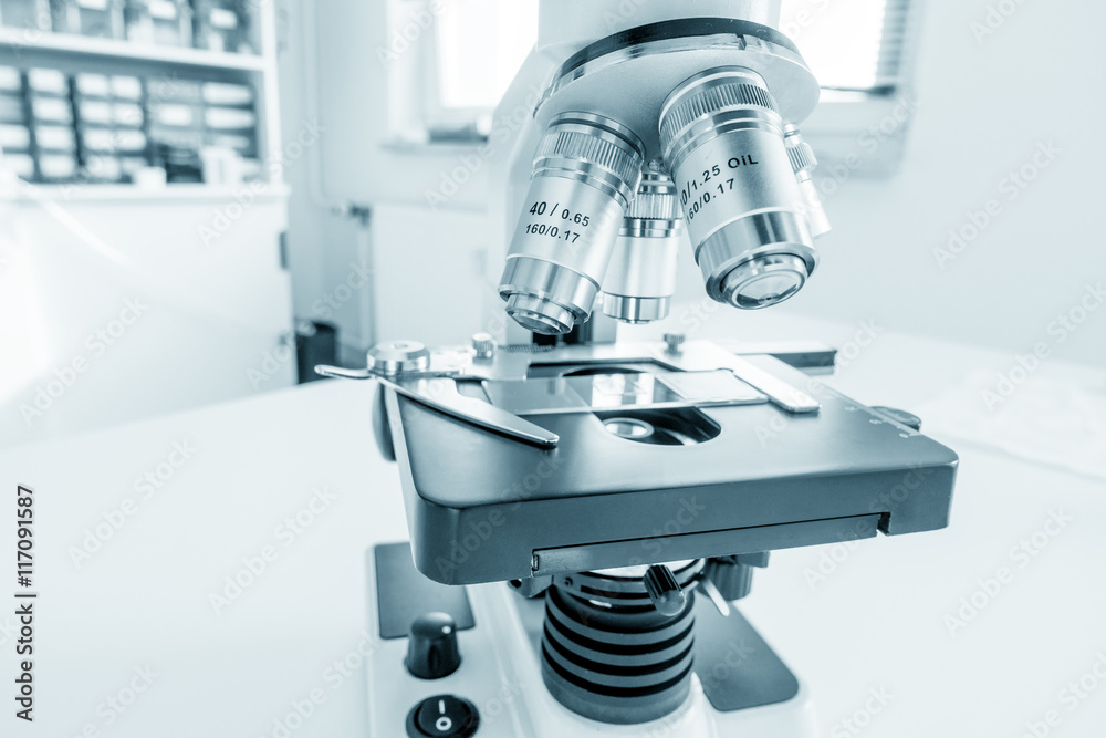 Science microscope on lab bench. Microbiology laboratory. Blue toned ...