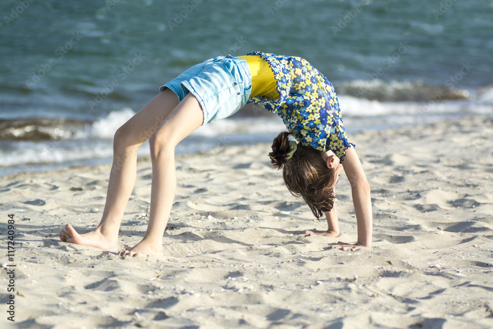 Girl on the beach doing gymnastic exercises bridge Stock Photo | Adobe ...