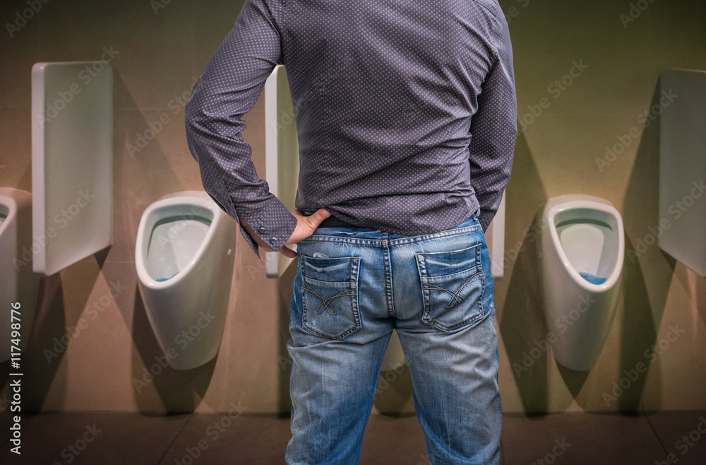 Standing man peeing to a urinal in restroom Stock Photo | Adobe Stock
