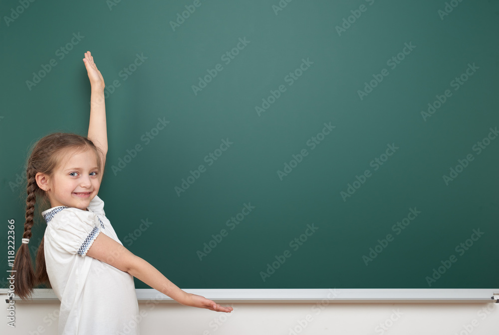 school student girl posing at the clean blackboard, grimacing and ...