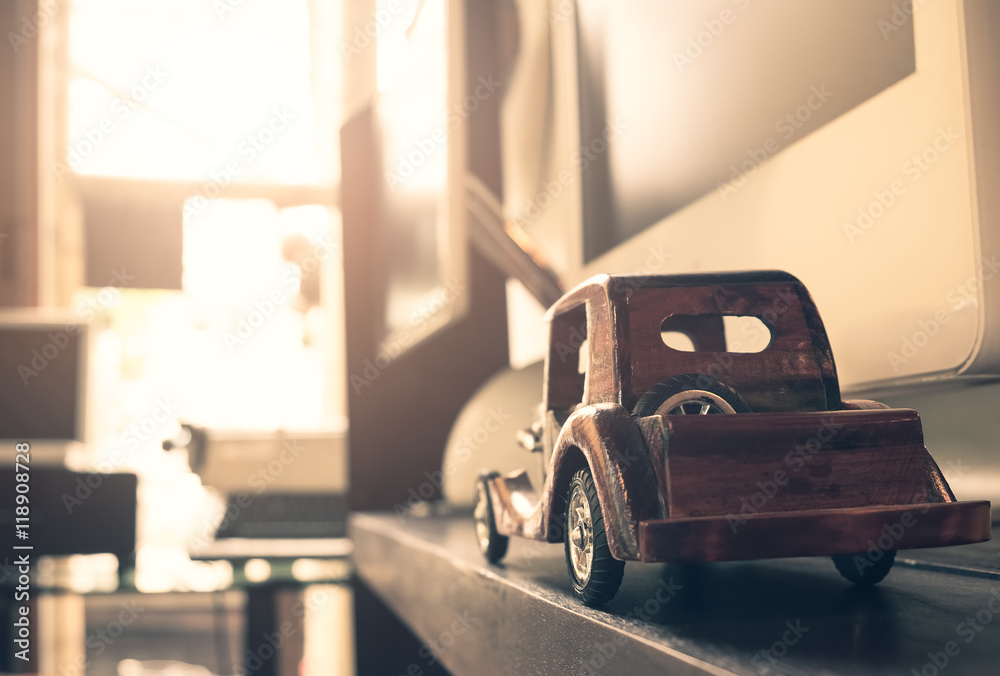 wooden toy car on hardwood balcony next to a window with sun light and ...