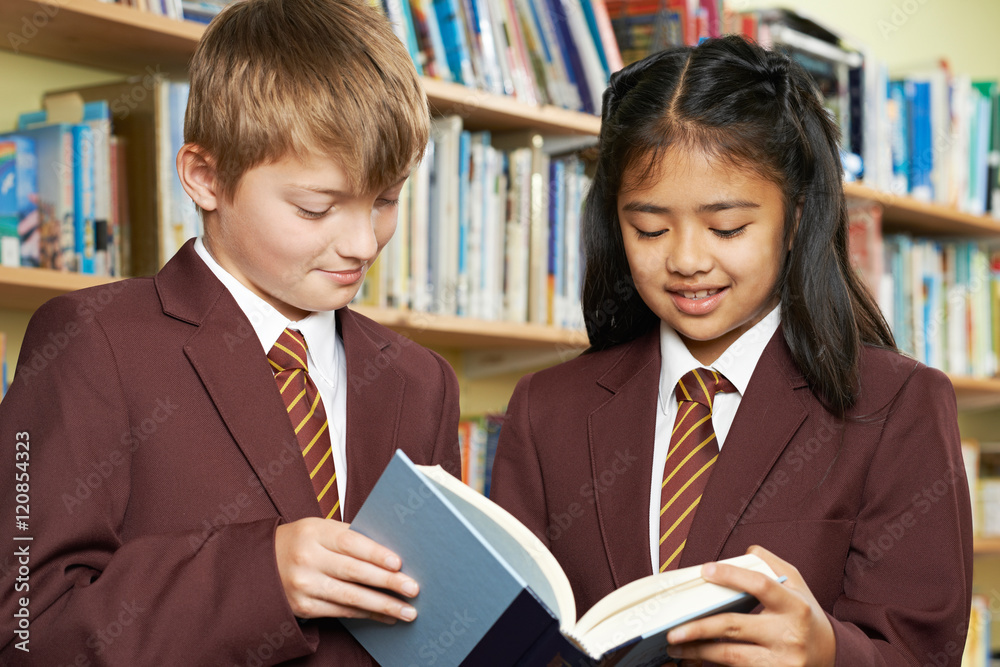 Pupils Wearing School Uniform Reading Book In Library Stock Photo ...