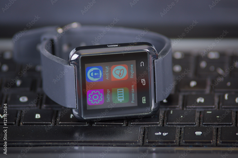 Smartwatch with screen lit up sitting on top of computer keyboard, very ...