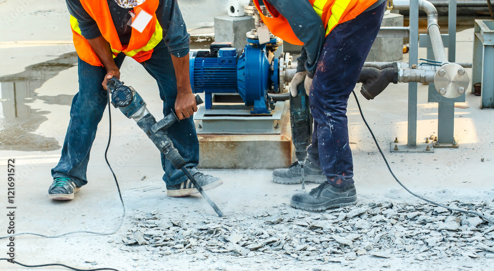 Foto de Stock Builder worker with pneumatic hammer drill equipment breaking concrete at road construction site Adobe Stock