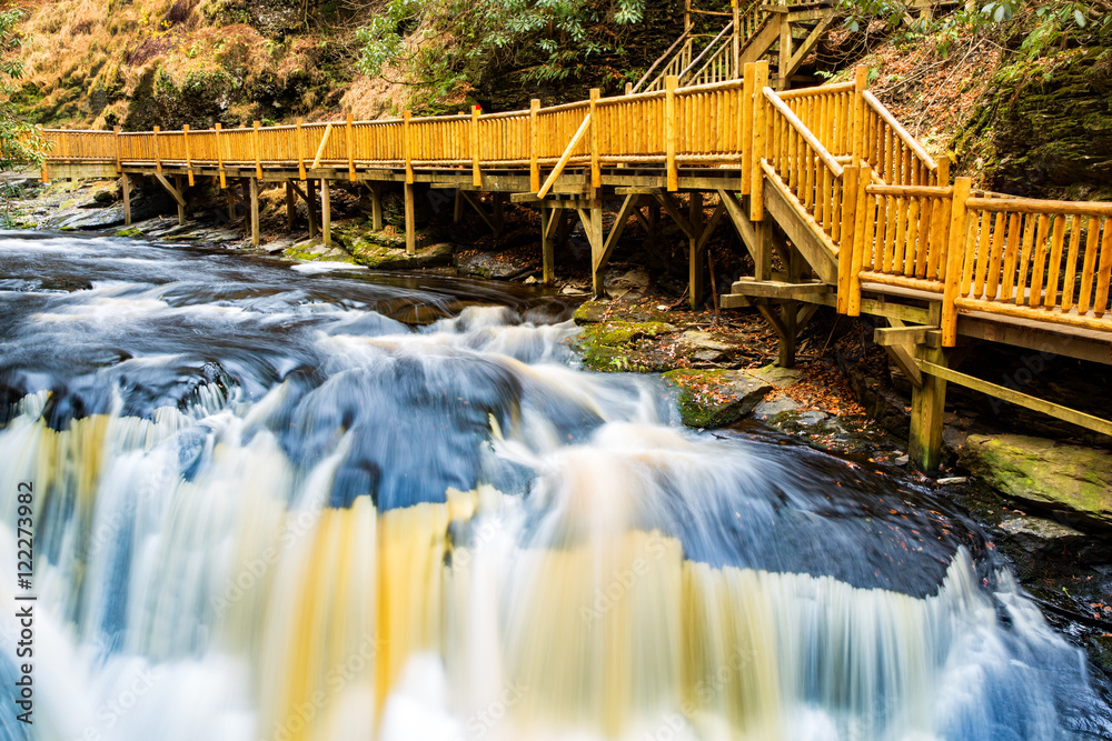 Waterfall on Little Bushkill creek. Wooden footpath borders the river ...