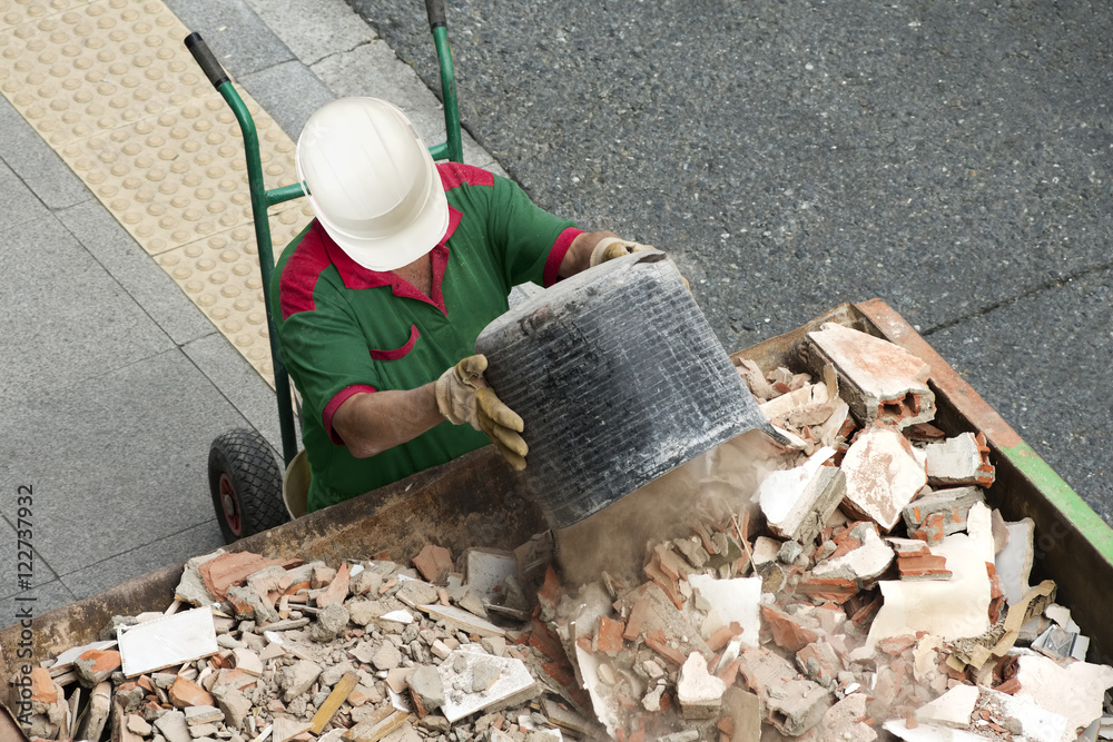 bricklayer mason worker depositing waste of bricks and tiles in rubble ...