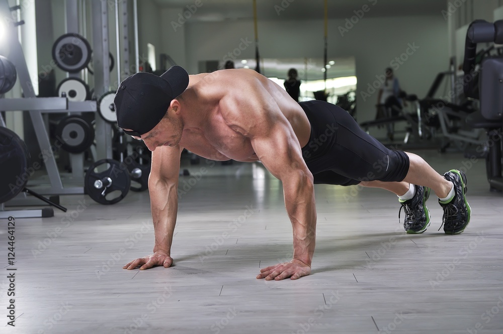 Handsome powerful athletic man performing push ups at the gym. Strong ...