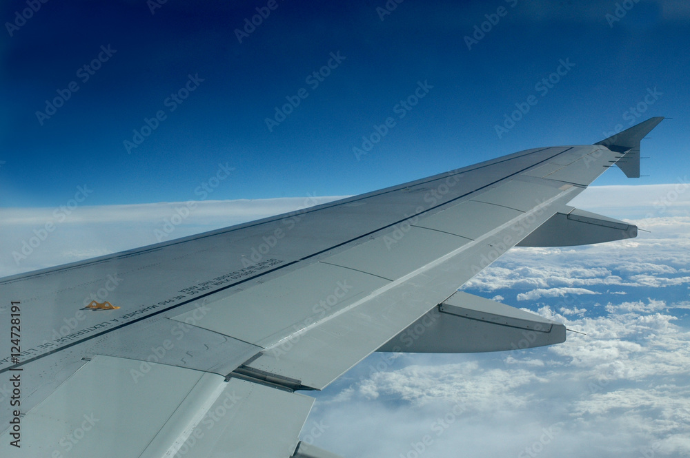 Aile d'avion en vol vue à travers un hublot passager, volets fermés ...