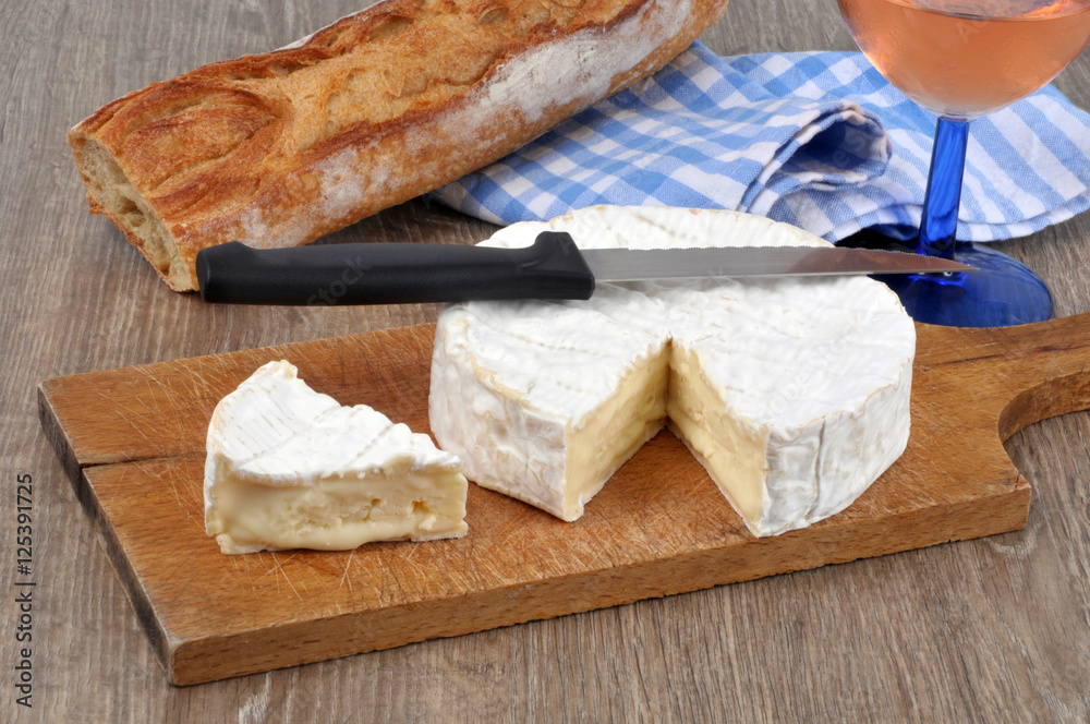 Camembert posé sur une planche à découper avec du pain et un verre de ...