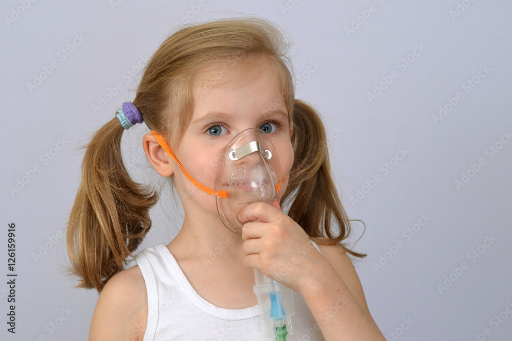 Child, kid (little girl) with inhaler (nebulizer) makes the procedure ...