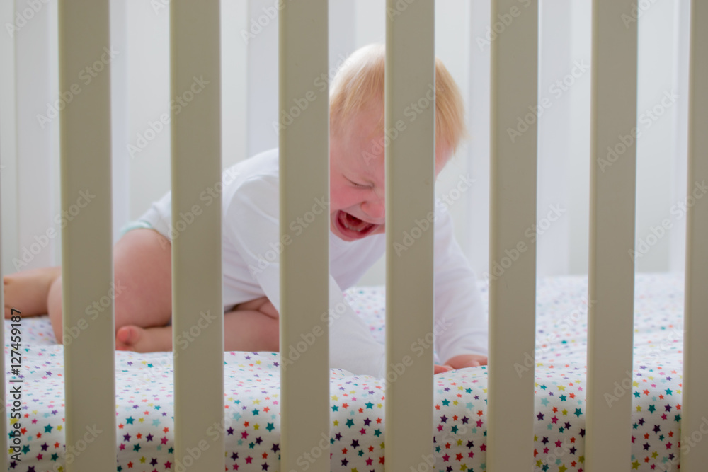 Baby boy crying in his cot refusing to sleep with a look of pure Stock ...