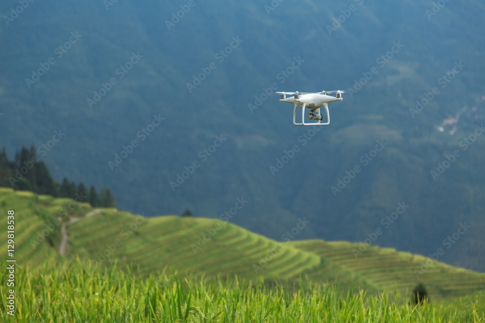Hovering drone taking pictures of green hills. White drone flying over ...