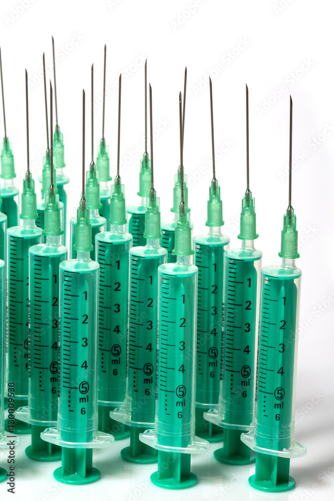 Rows of 5 ml standing green medical syringes. All syringes needles ...