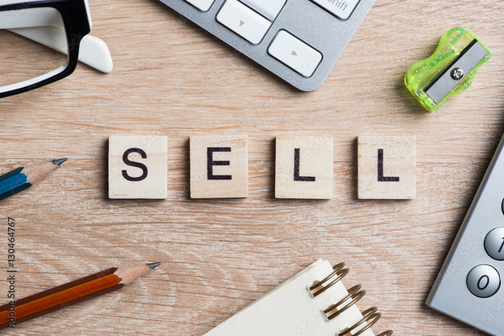 Office stuff and SELL word spelled with wooden blocks on workplace ...