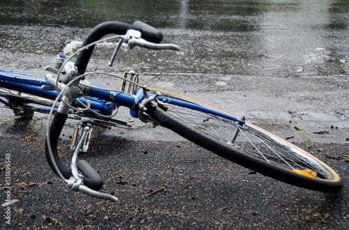 Bicycle fallen over on road in the rain Stock Photo | Adobe Stock