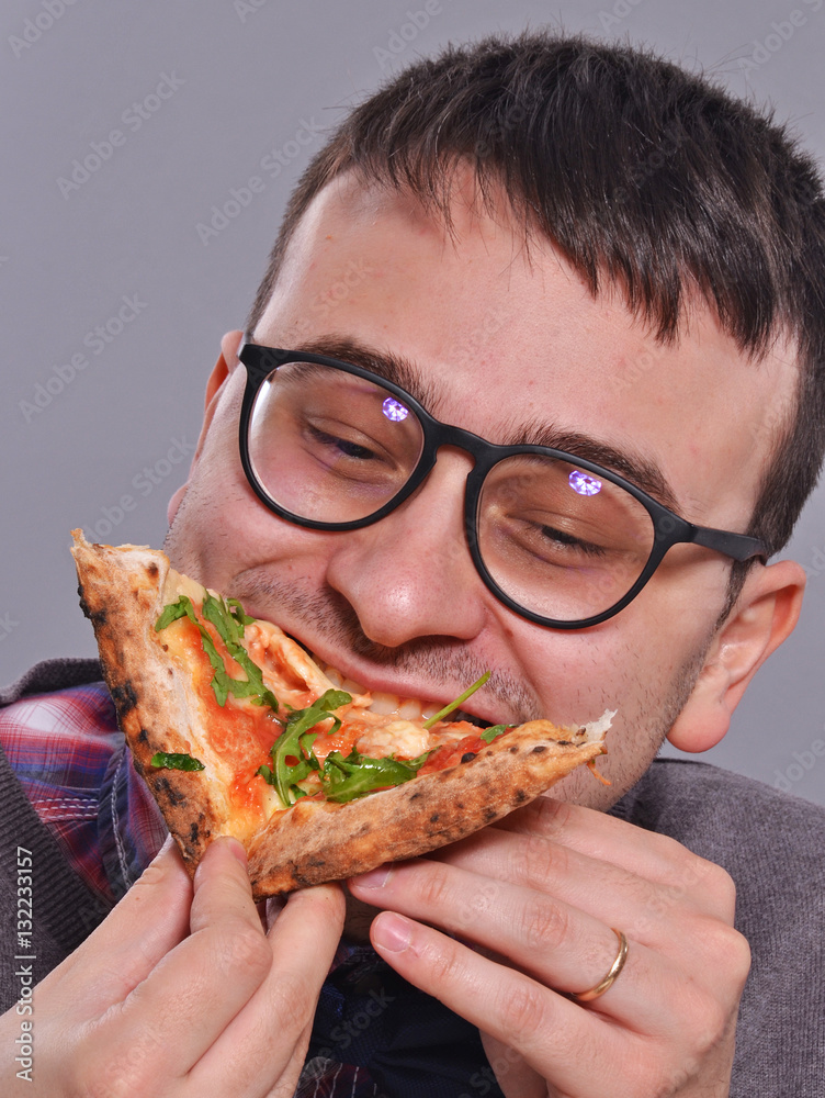 Foto de Stock Retrato de un hombre nerd comiendo pizza. | Adobe Stock