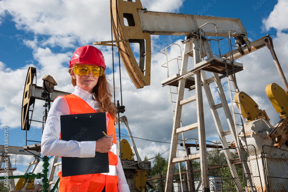 Beautiful woman engineer in the oilfield wearing red helmet and work ...