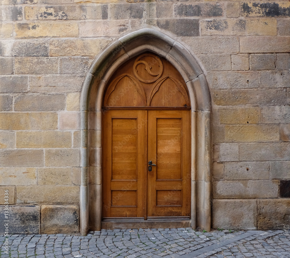 Wooden double door with pointed gothic arch and ornaments above the ...