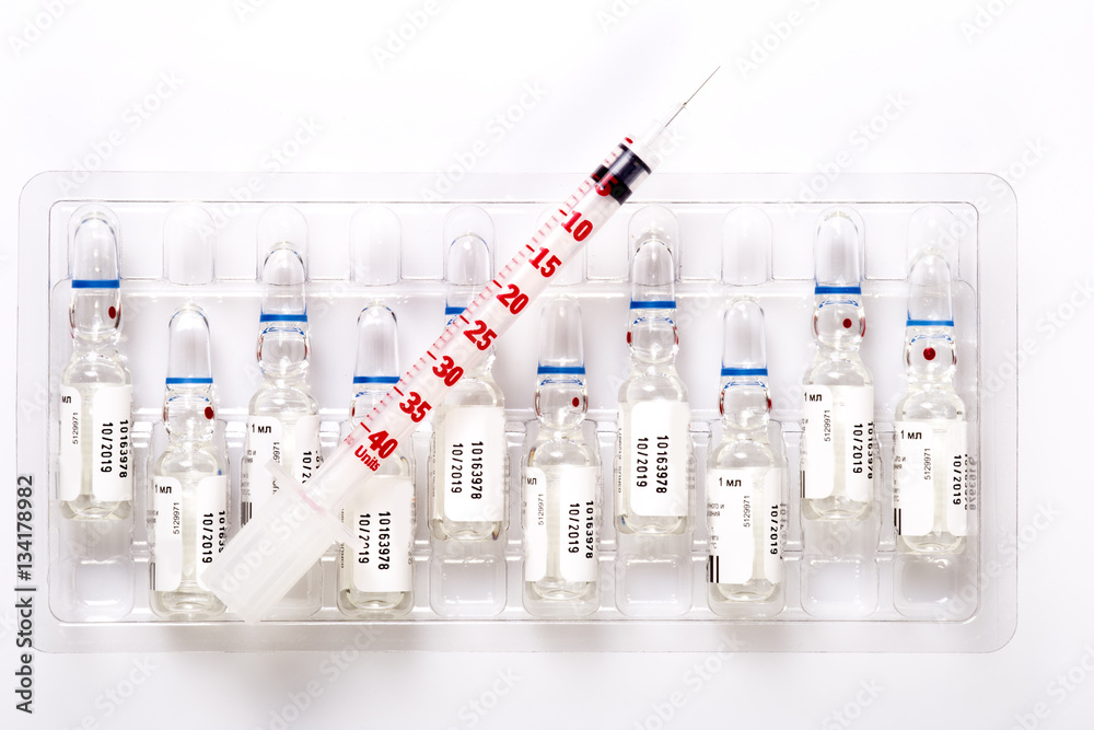 Plastic holder with painkiller drug ampules. Medical syringe lying on ...