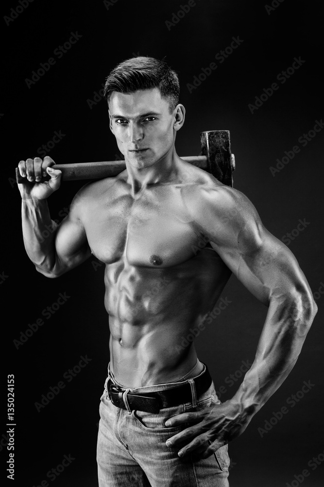 Muscular man with naked torso holding big hummer. Isolated on dark grey ...