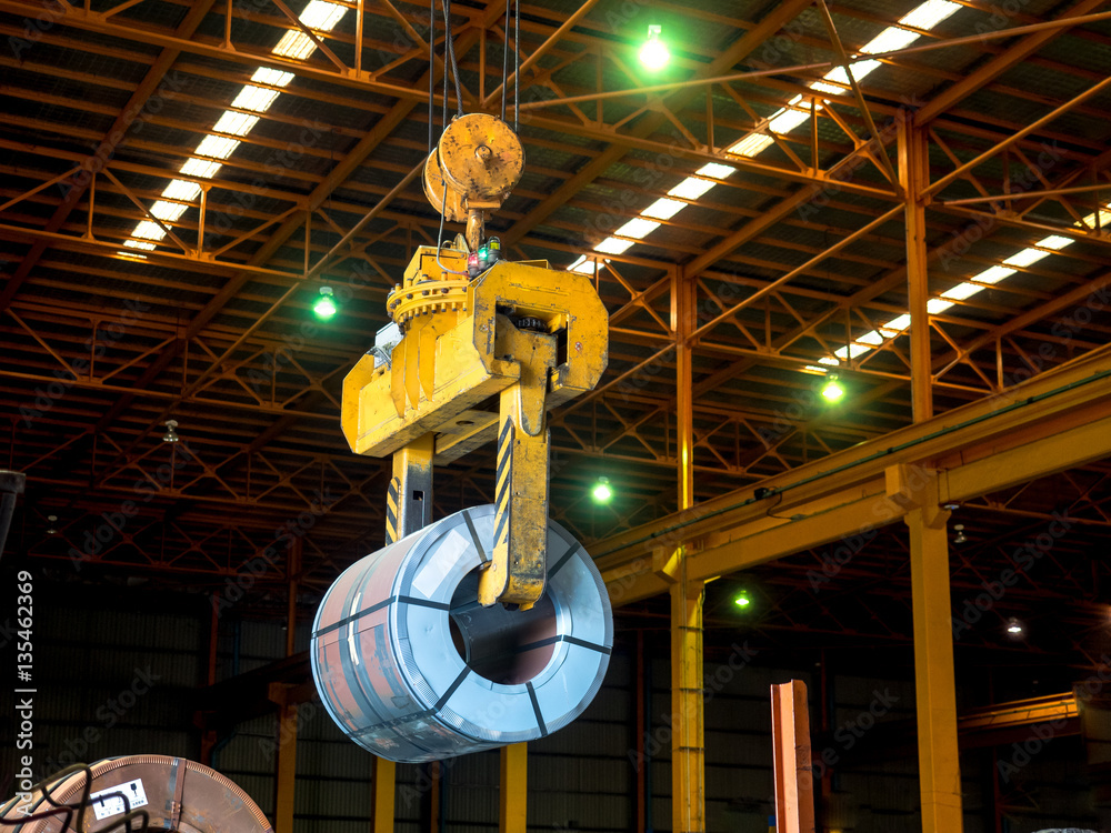 An overhead crane -Coil tong carrying a steel coil to a designated ...