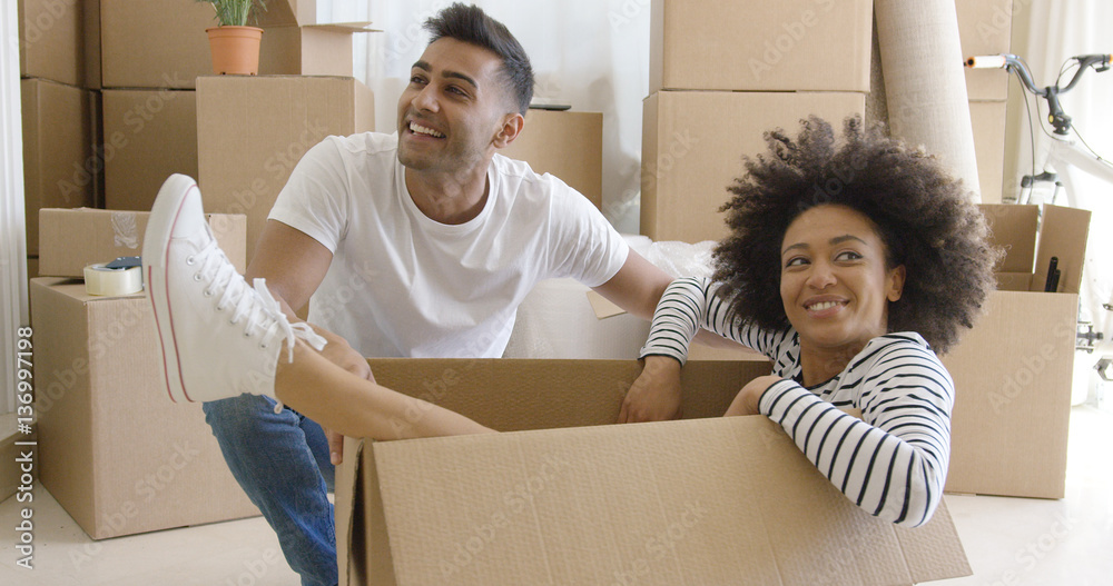 Smiling young woman in a cardboard carton with her grinning alongside ...