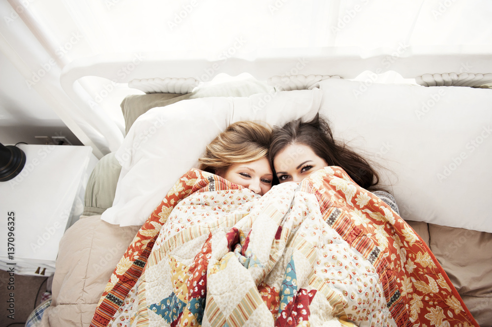 Two friends hiding under covers in bed Stock Photo | Adobe Stock