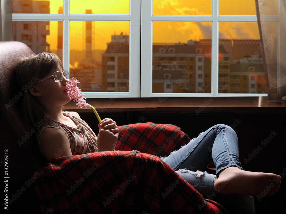 teenager in a rocking chair by the window. Woman smelling a spring ...